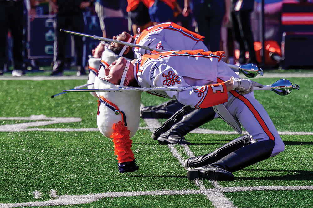 The Fighting Illini Marching Band drum majors do a deep back bend as ...